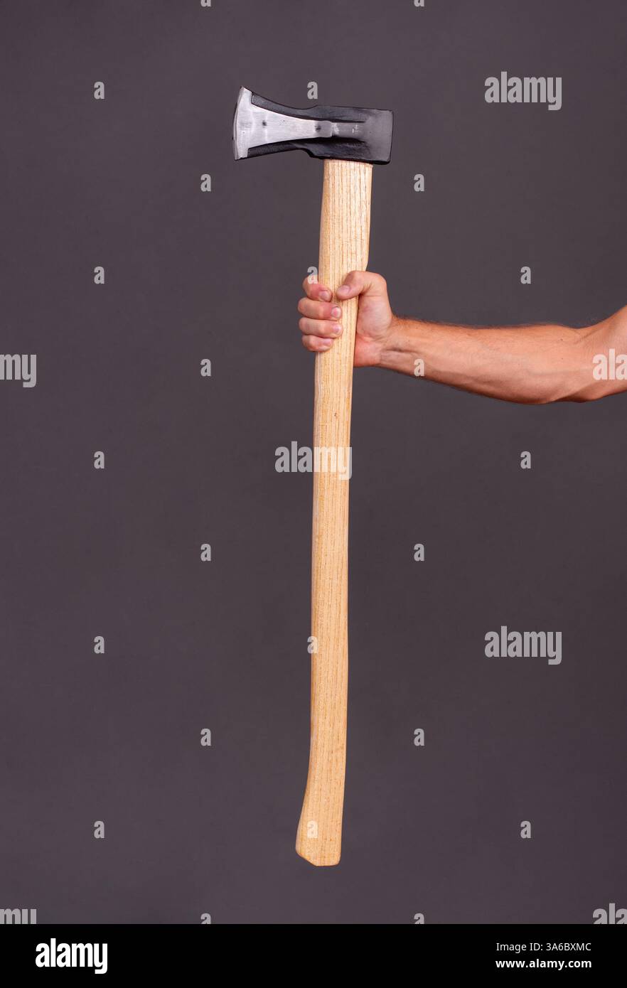 A man's hand holding an axe for chopping wood. vertical Stock Photo - Alamy