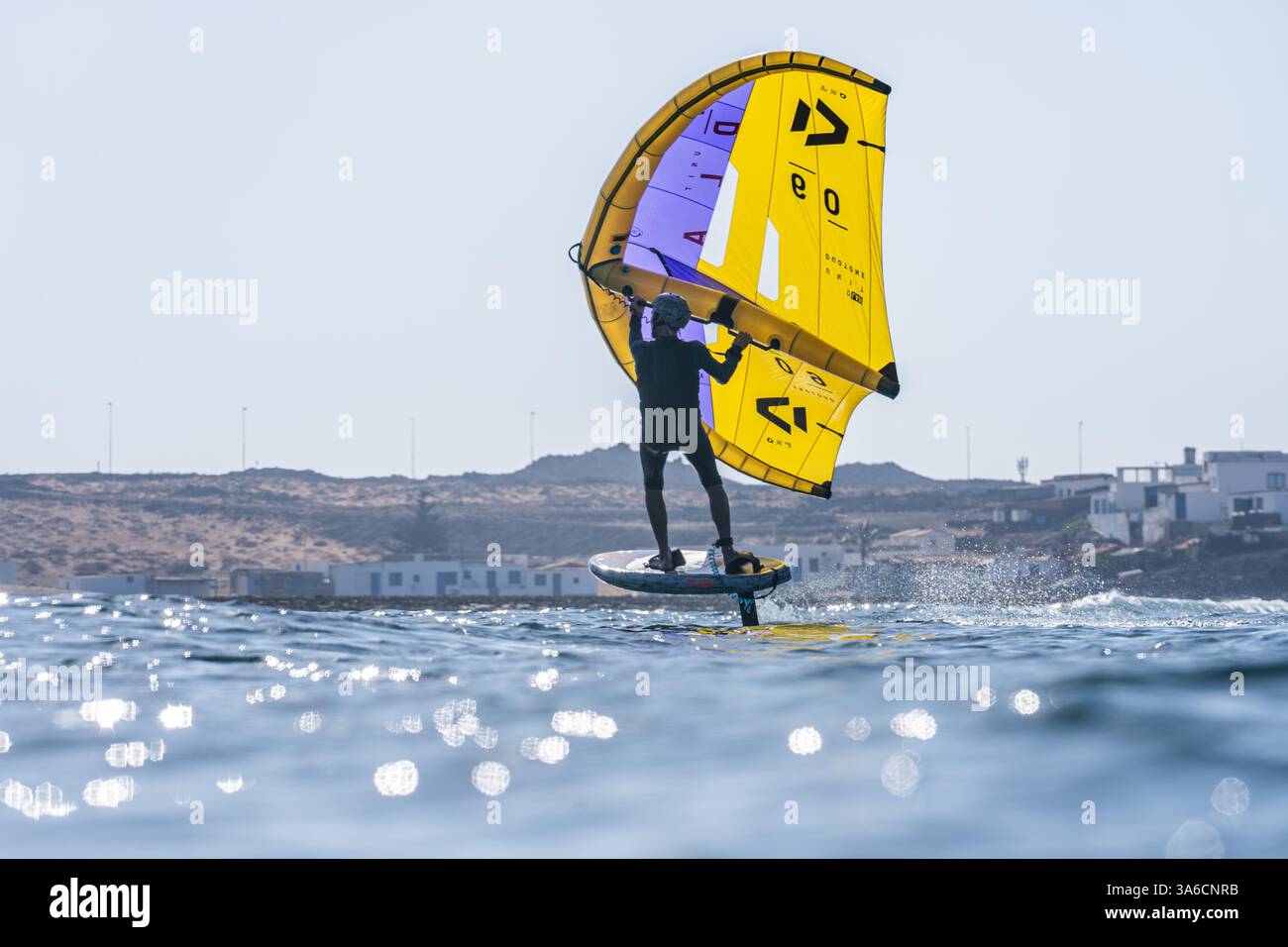 A man wingfoils at sea using a hand held inflatable wing, riding a ...