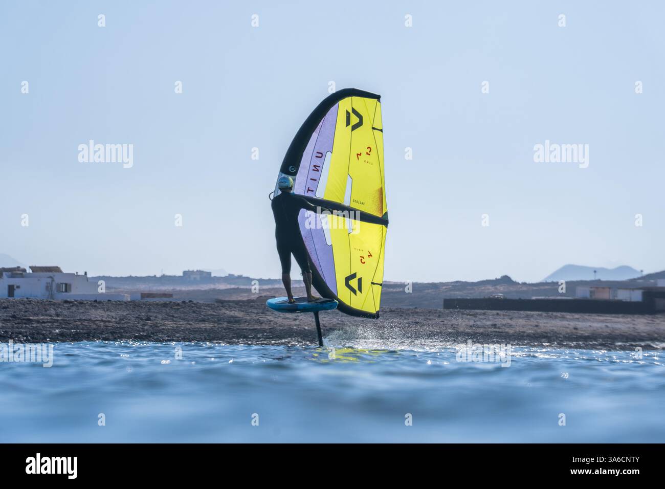 A man wingfoils at sea using a hand held inflatable wing, riding a ...
