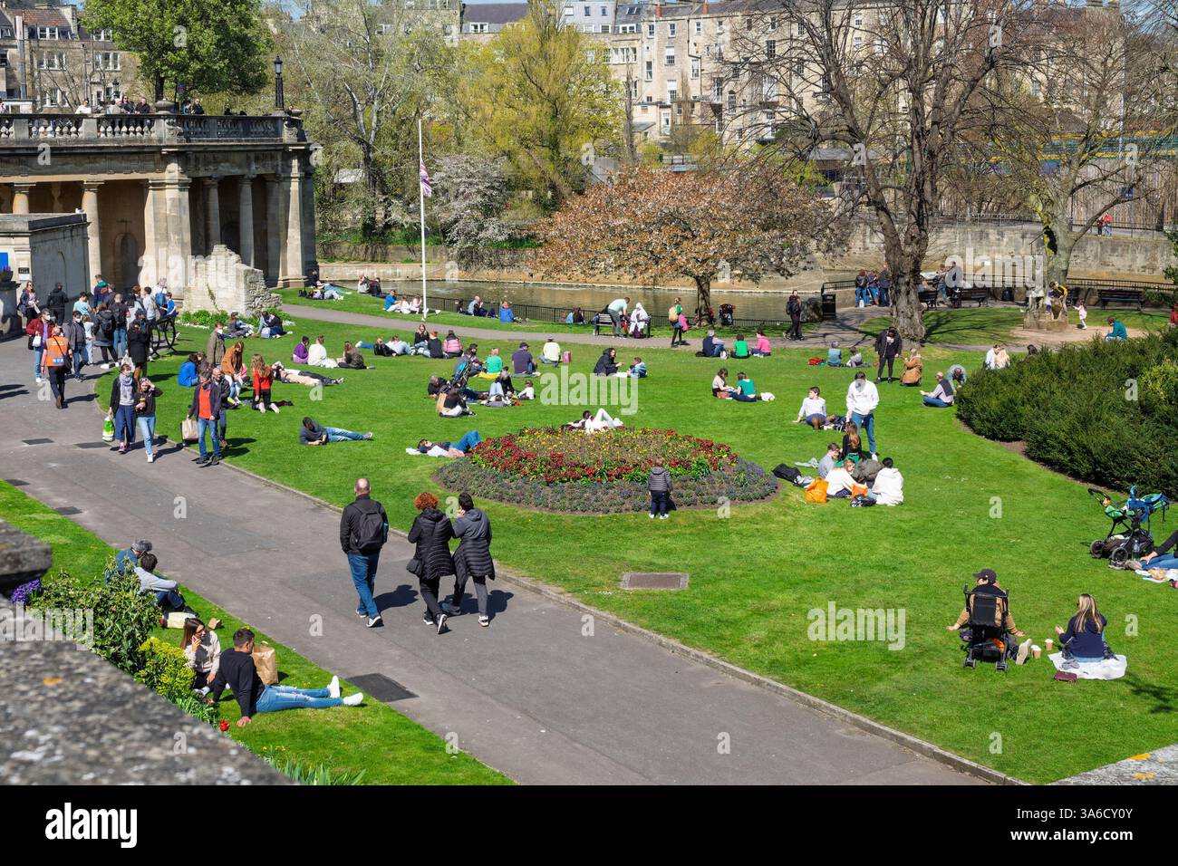 People enjoying warm weather sitting in Parade Gardens, Bath, UK. The ...