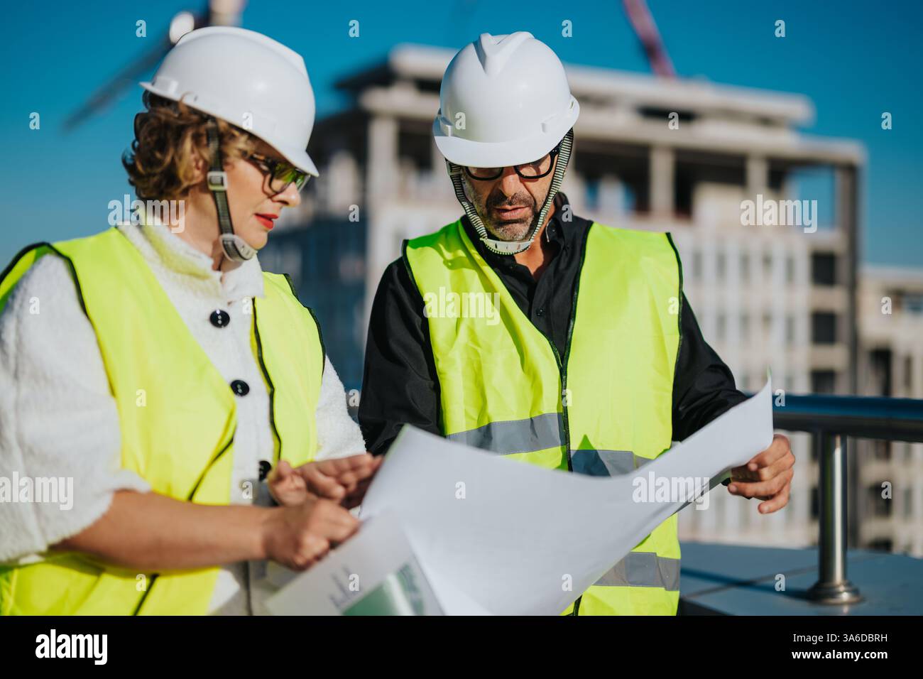 Architects reviewing construction plans at a building site Stock Photo ...