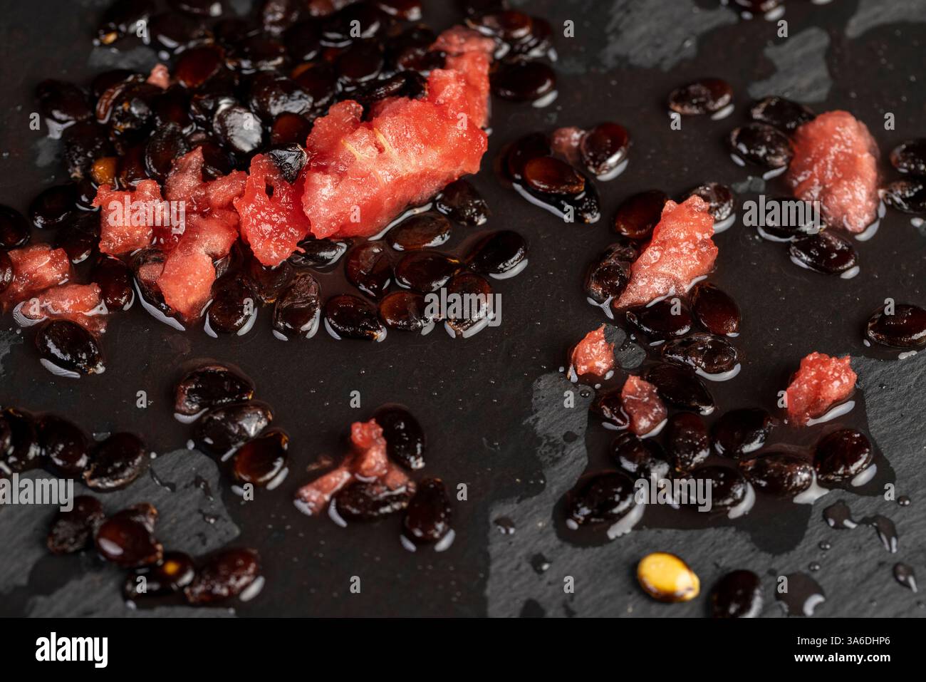 watermelon seeds and red pulp on black slate, watermelon seeds after ...