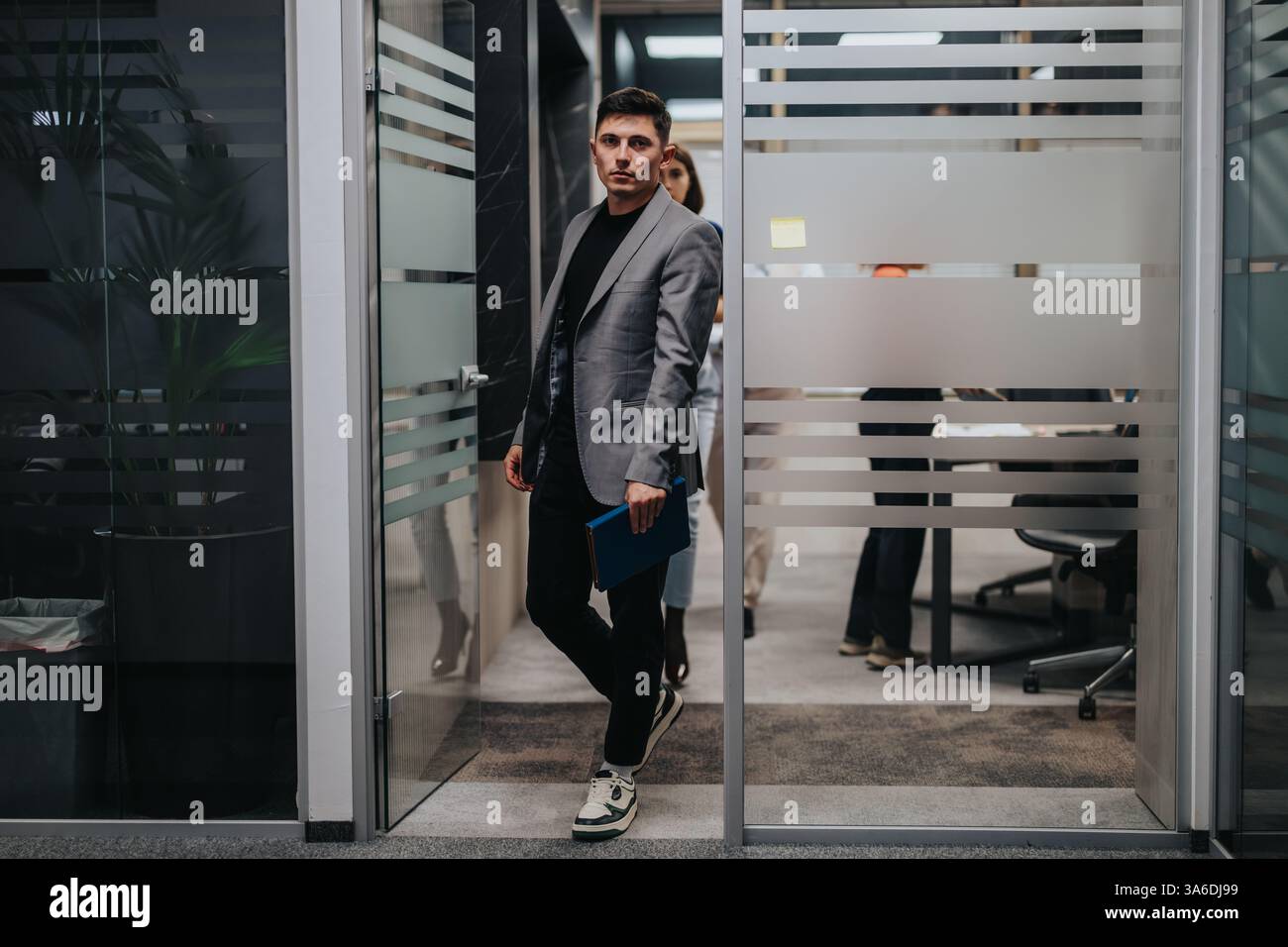 Young employee walking through modern office with glass partition walls ...