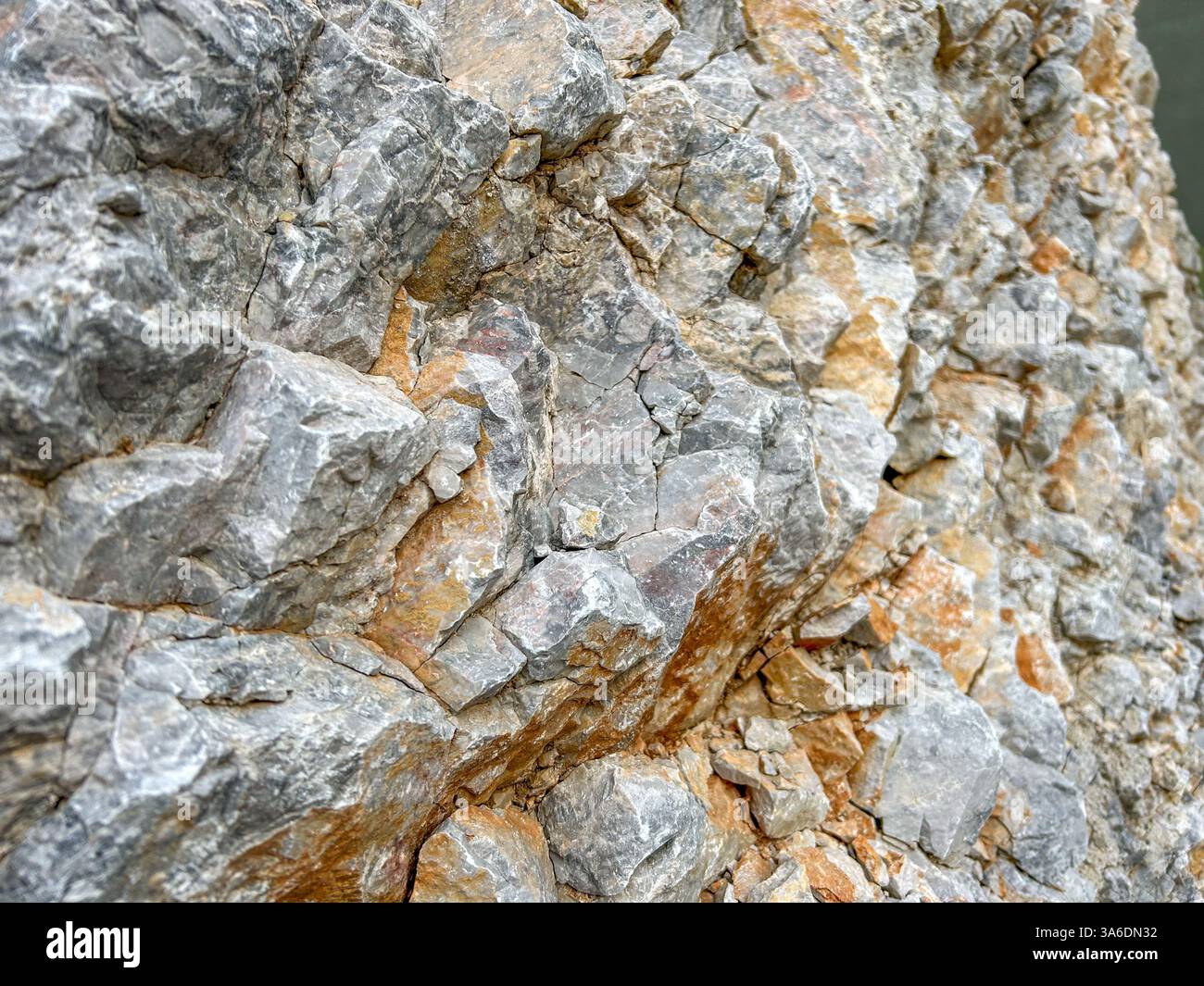 A rugged, broken stone cliff with sharp edges and visible layers ...