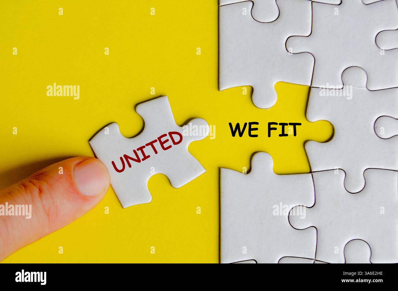 Hand placing missing jigsaw puzzle with text United We Fit representing ...