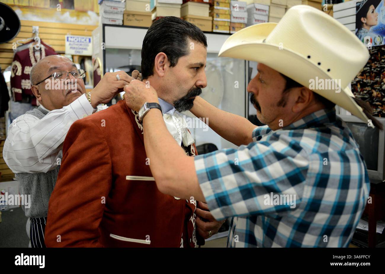 JORGE TELLO, left, does the final touches to the bow of a charro suit ...
