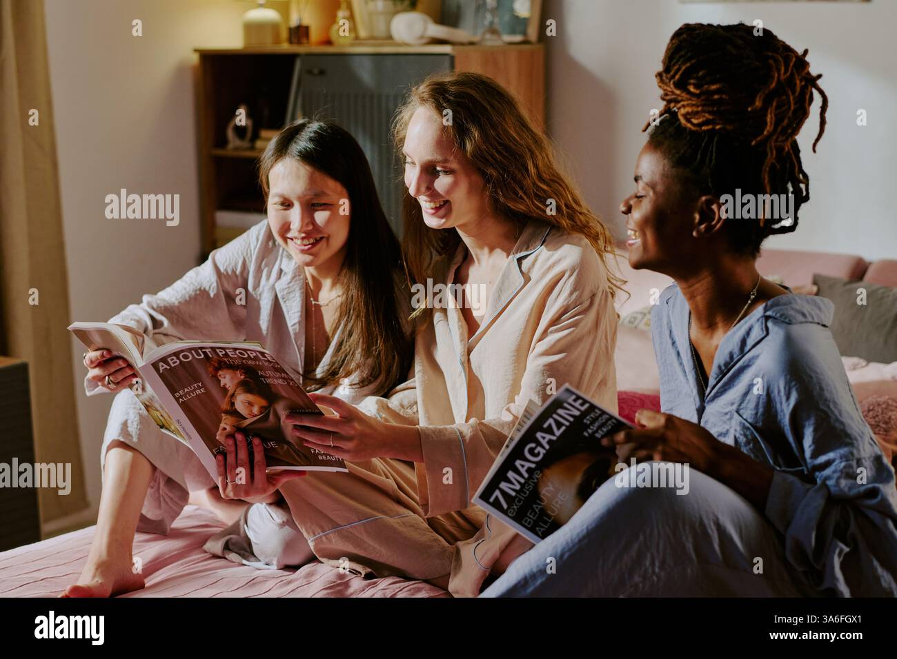 Medium shot of biracial young adult best friends in silk pajamas ...