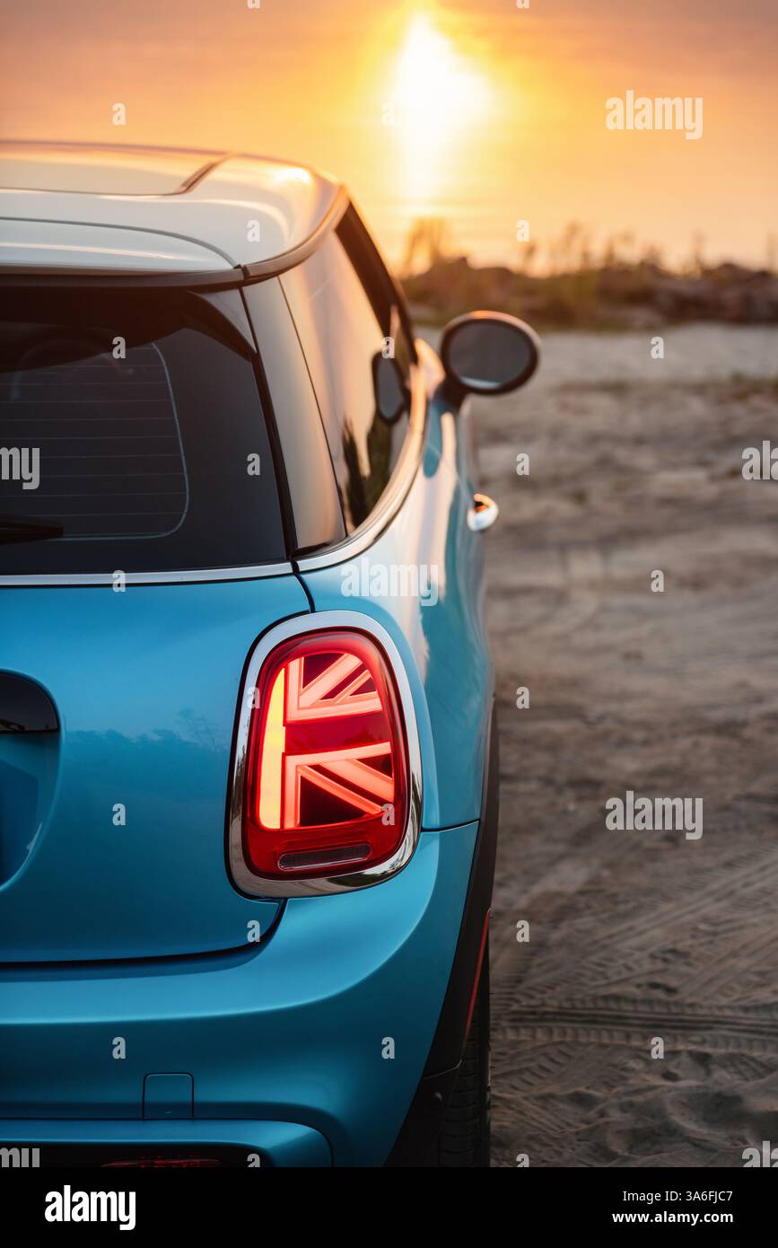 Blue Mini Cooper on a beach at sunset. Rear view of british hatchback ...