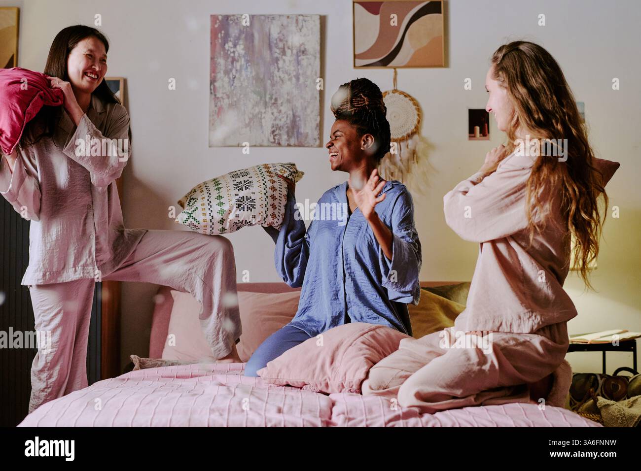 Three biracial best friends dressed in pajamas smiling and laughing ...