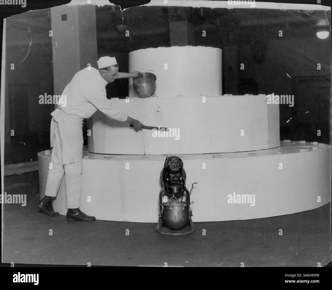 A baker decorates a large cake for the Minneapolis Diamond Jubilee Ball ...