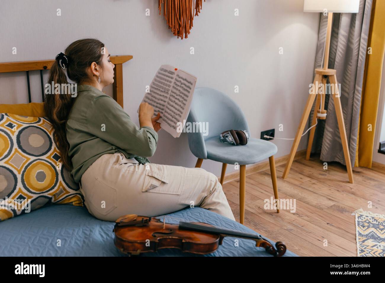 Focused woman practicing violin rhythm with sheet music guidance Stock ...