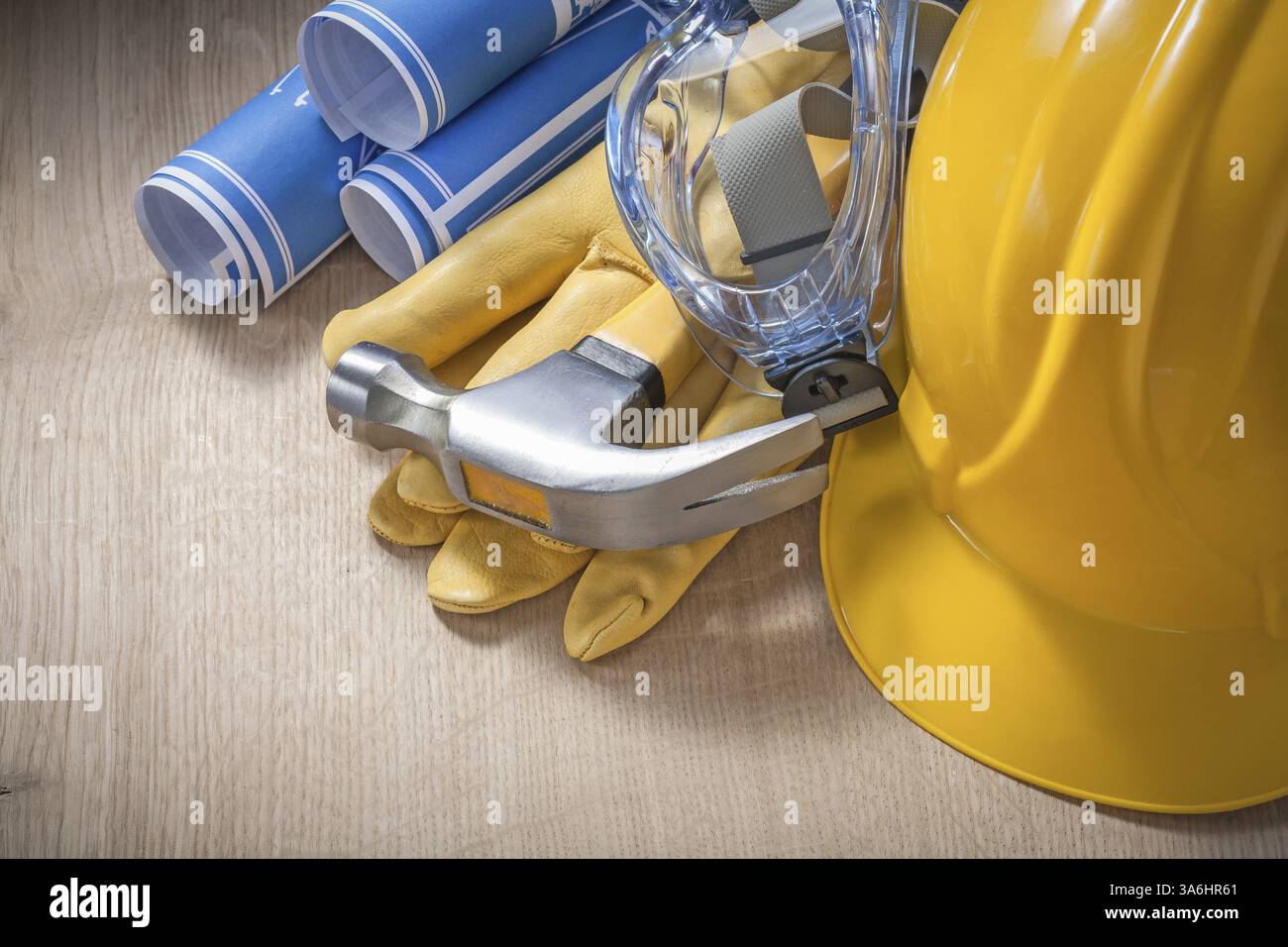 Safety workwear claw hammer rolled construction plans on wooden board ...