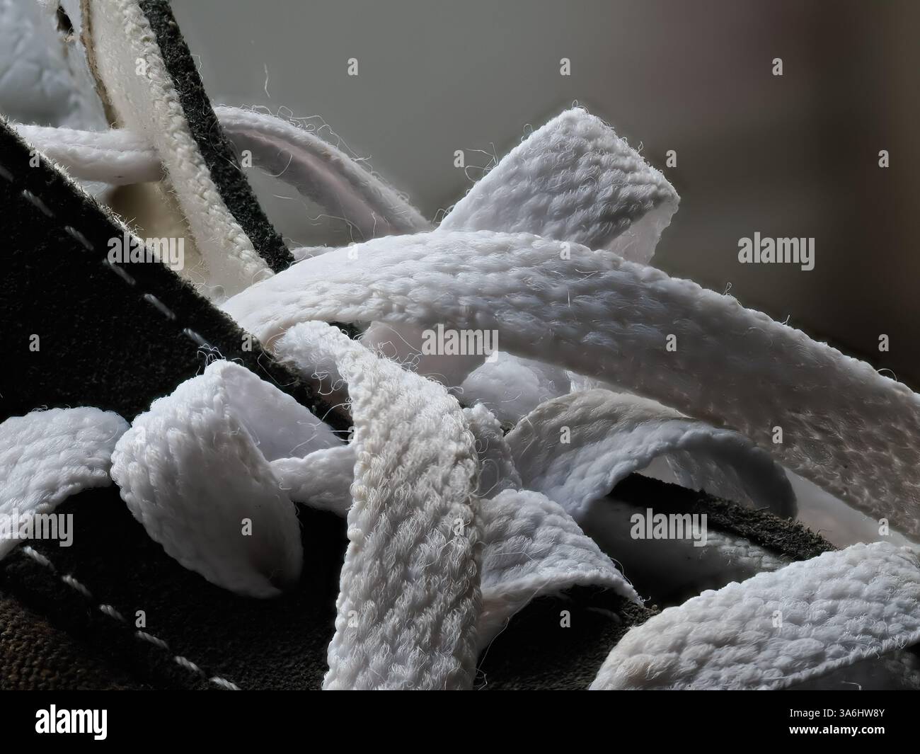 A white shoelace is shown in a close up. The shoelace is white and ...