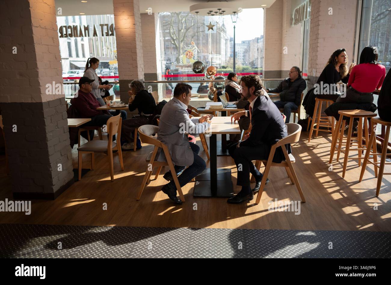 Businessmen carrying out a meeting whilst sat in a busy Pret A Manger ...