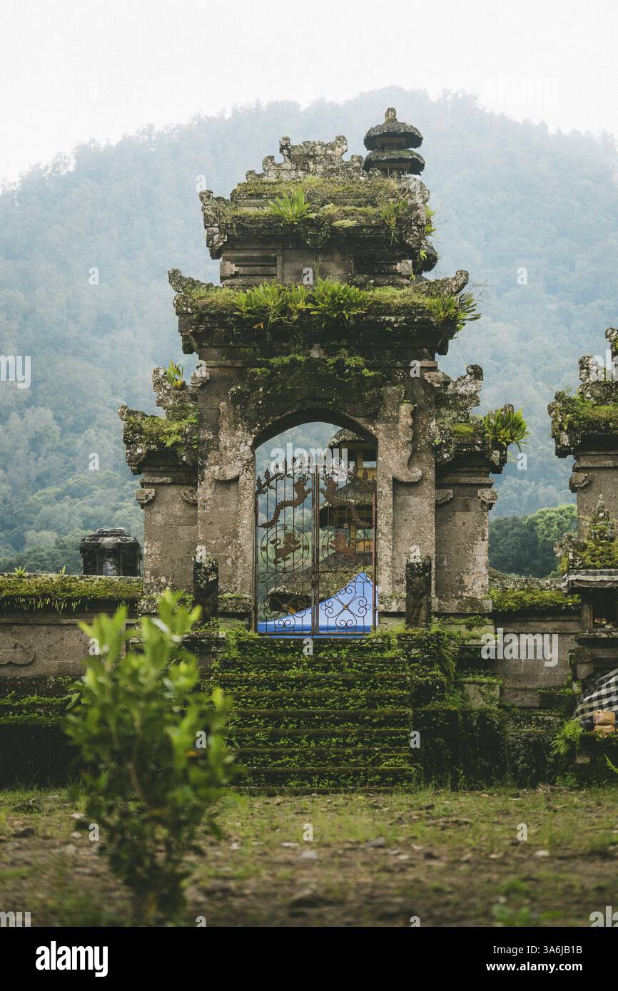 Entrance gate to a temple in front of a wooded mountain landscape ...