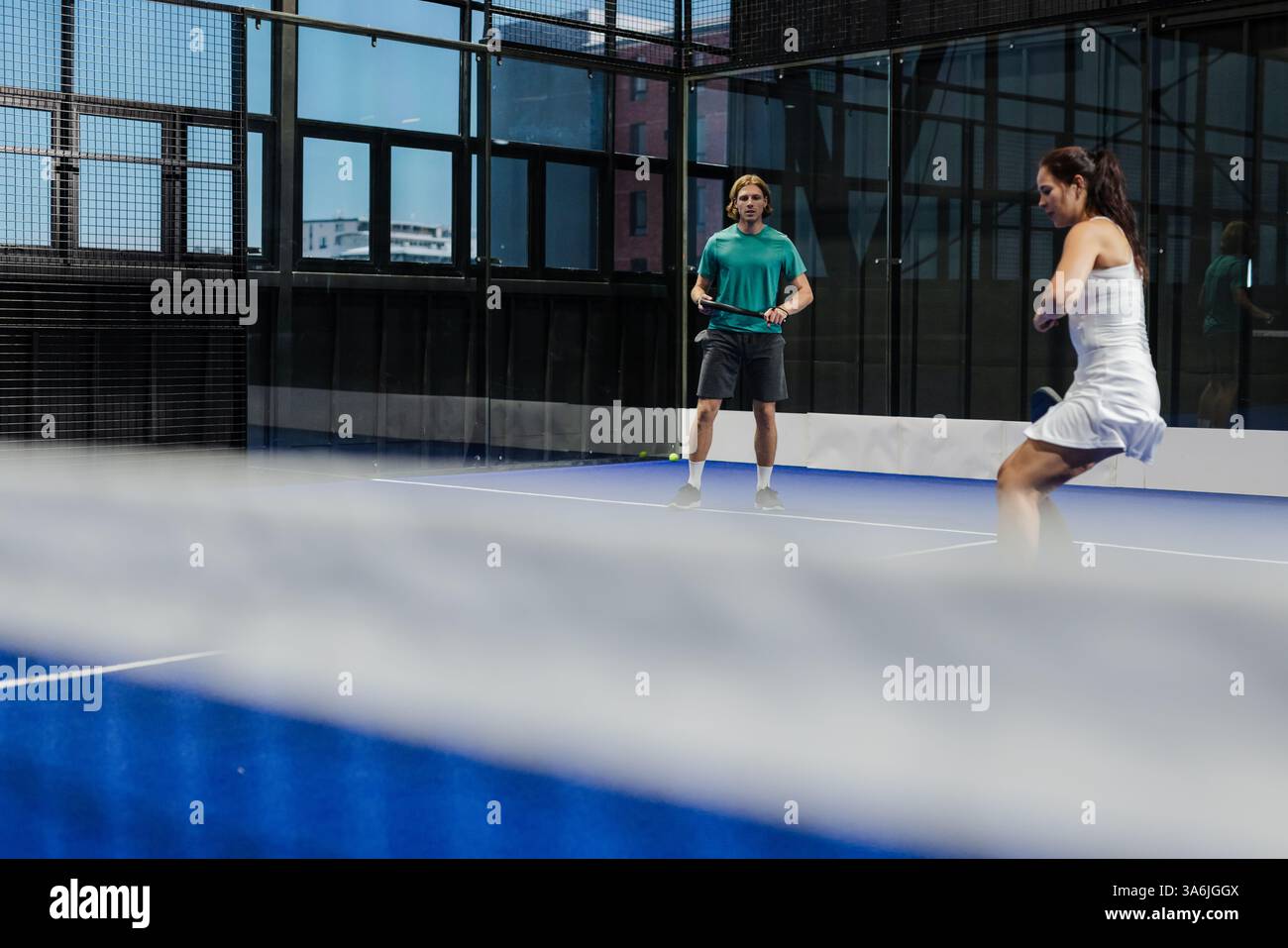 Playing padel tennis, man and woman focusing on game in modern court ...