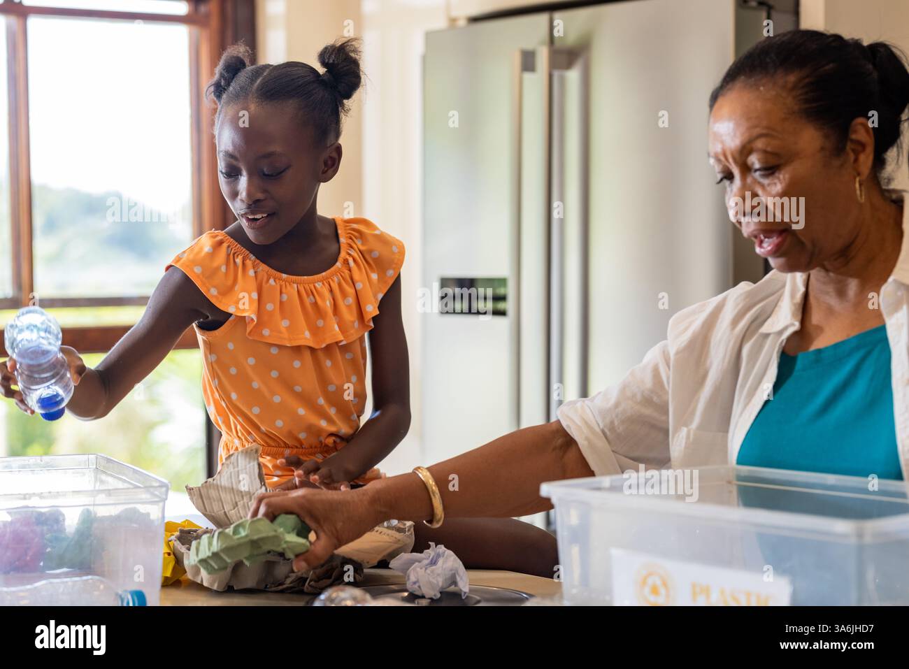 In kitchen, grandmother and child sorting recyclables, spending quality ...
