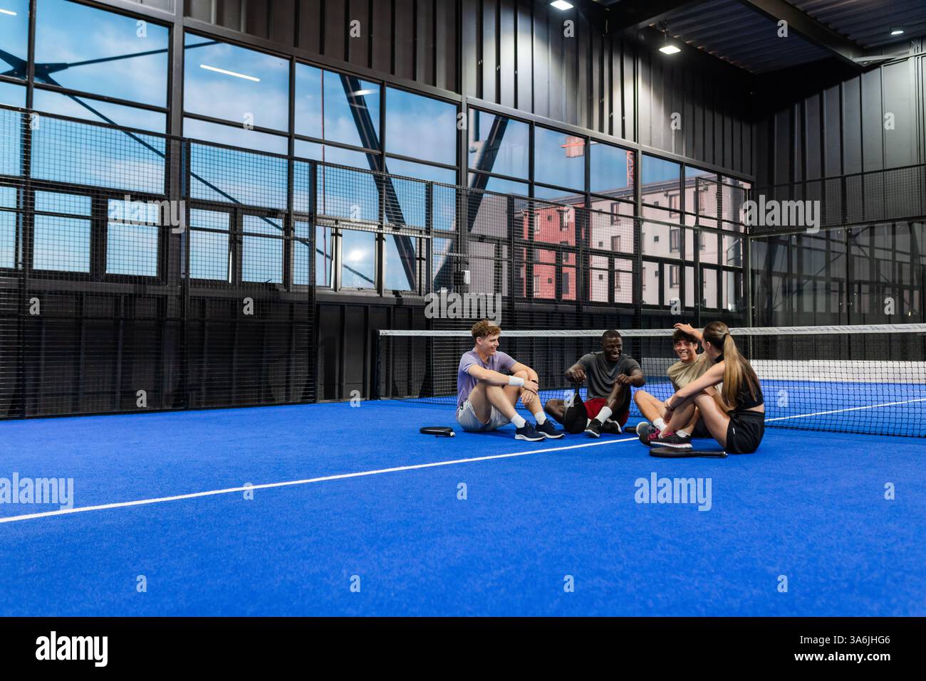 Group of friends sitting on padel court, relaxing after fun game, copy ...