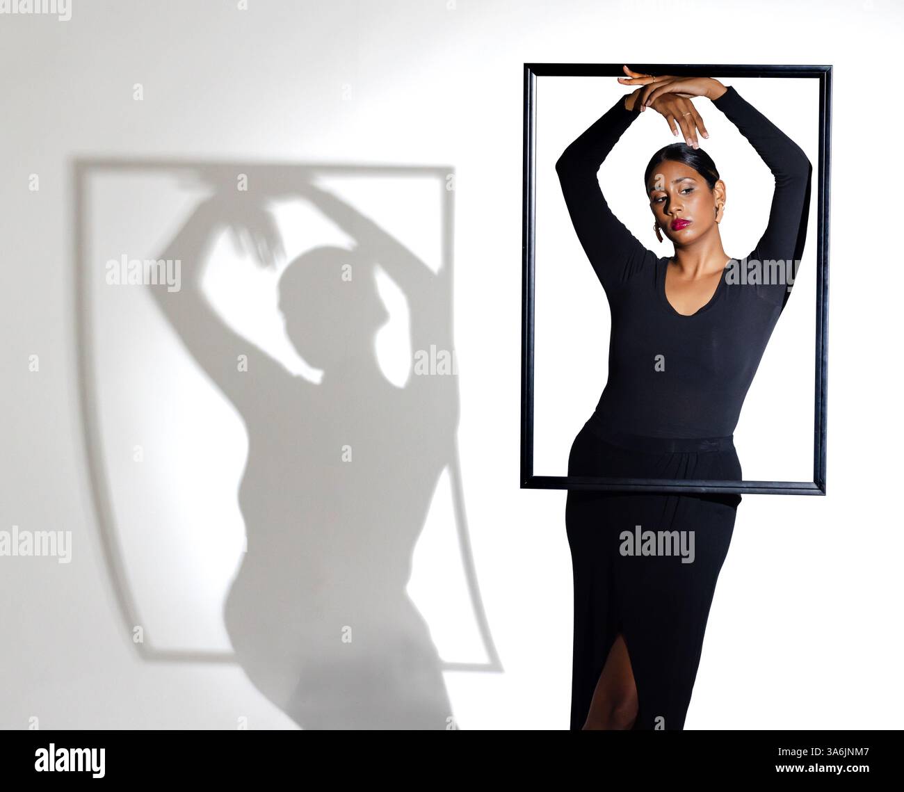 Elegant woman posing with frame, creating artistic shadow on wall Stock Photo - Alamy