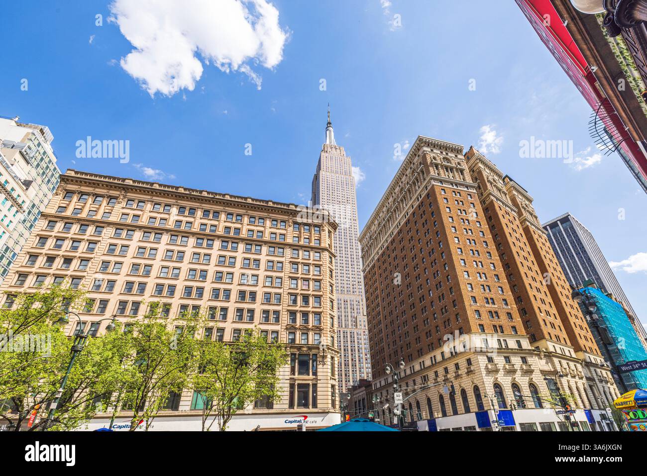Empire State Building and surrounding historic buildings under blue sky with white clouds on ...