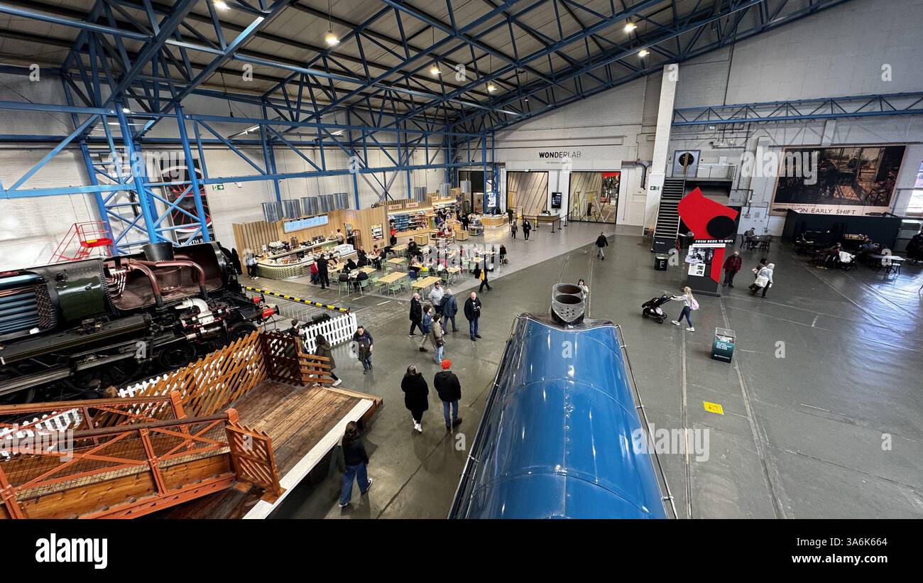 Wide shot of an indoor museum featuring trains, a cafe area with people ...