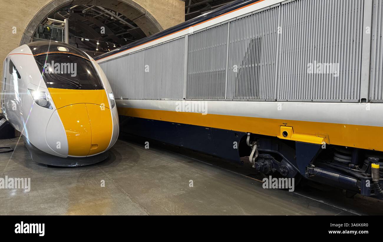 Two adjacent train cars, one white and yellow, the other white, blue ...