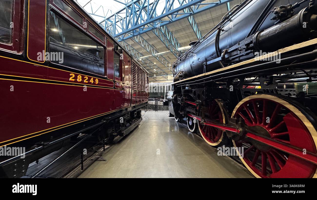 Two vintage trains, one maroon passenger car and one black steam engine ...