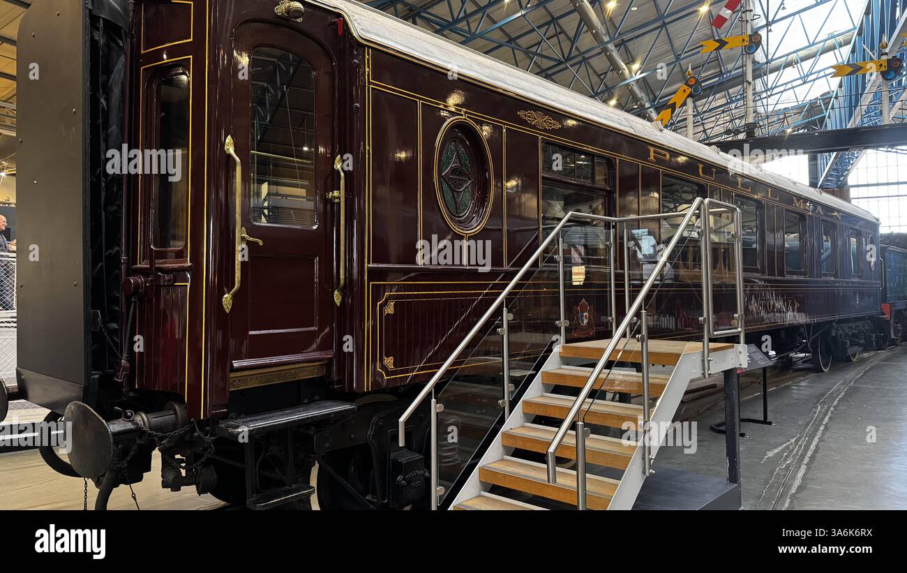 A maroon-colored Pullman train car is displayed indoors with a ...