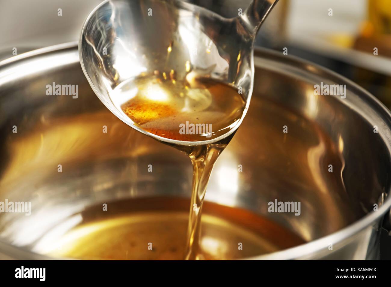Pouring used cooking oil from ladle into saucepan, closeup Stock Photo ...