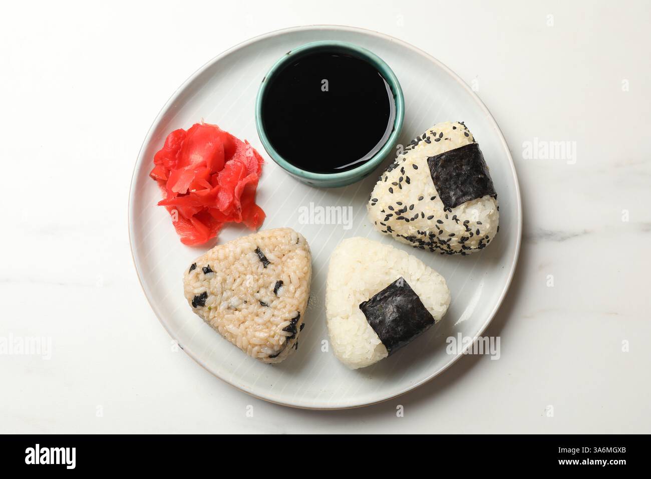 Rice balls (onigiri), soy sauce and pickled ginger on light table, top ...
