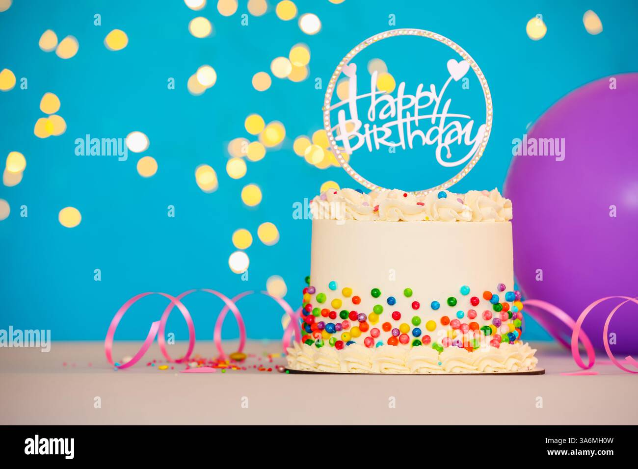 Tasty bento cake with colorful sprinkles, topper and balloon on table ...
