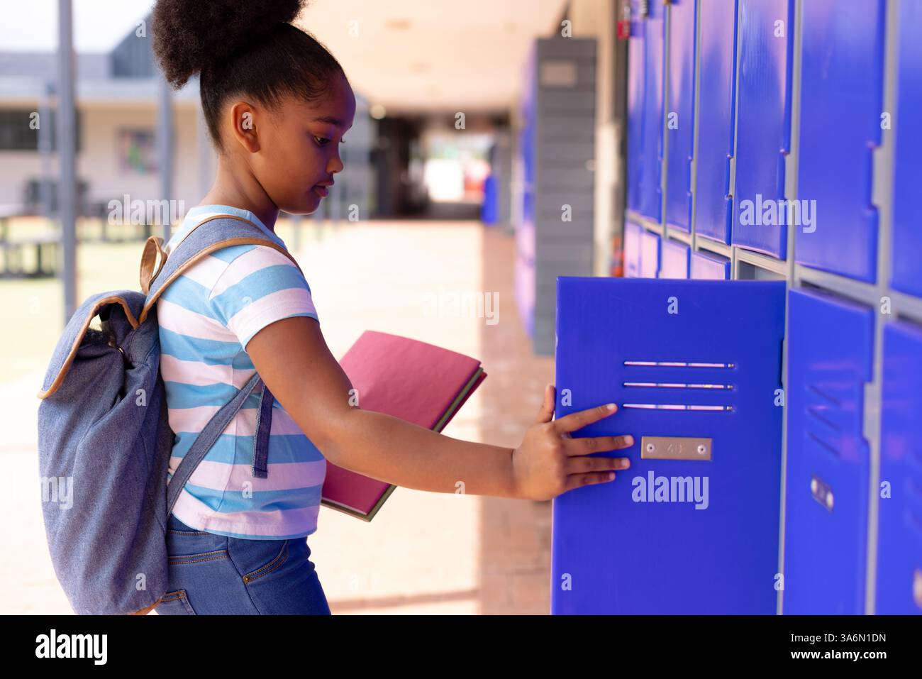 Student opening locker at school, holding book and wearing backpack. Education, back to school ...