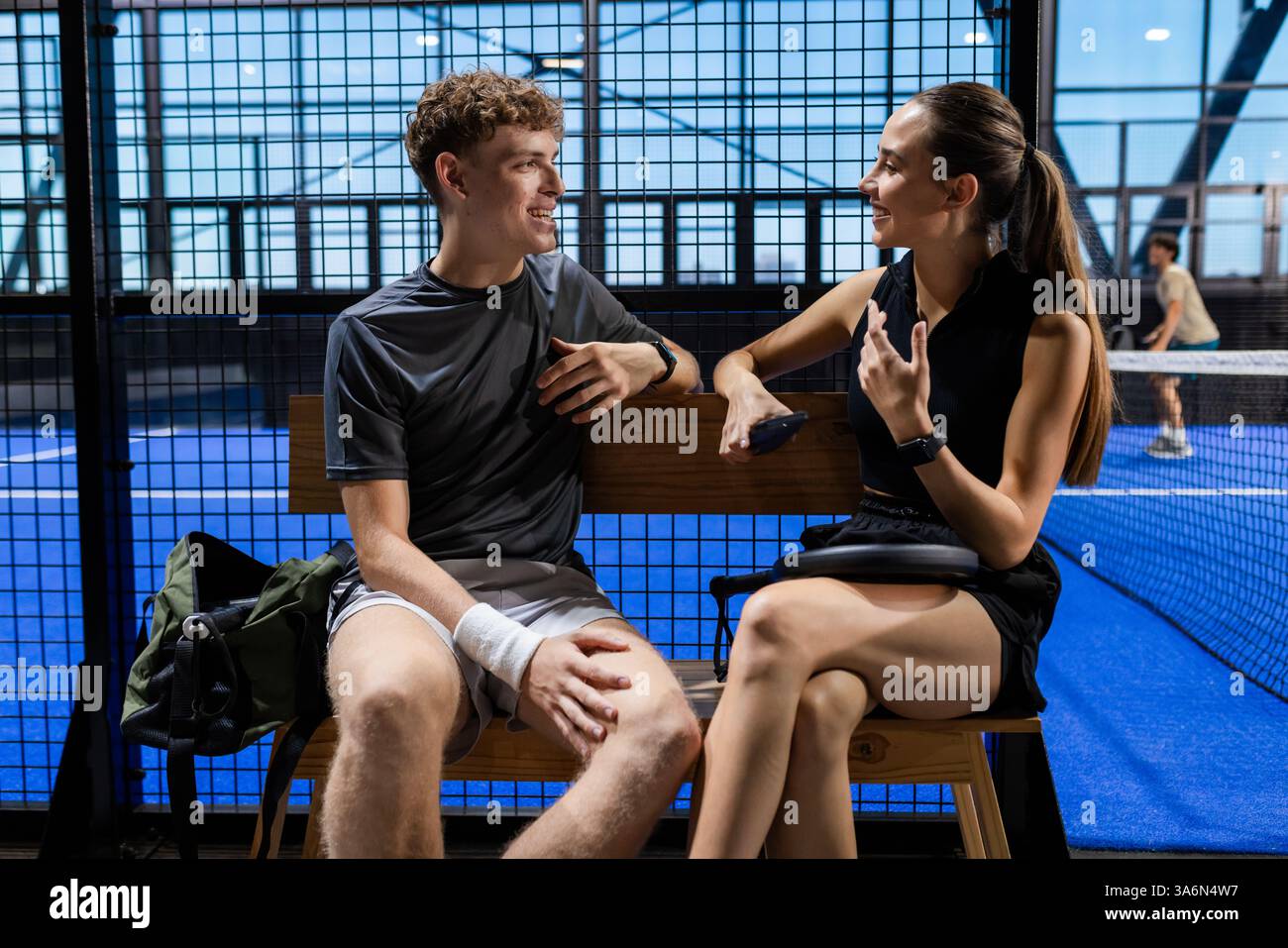 Young athletes chatting on bench after padel tennis match, enjoying ...