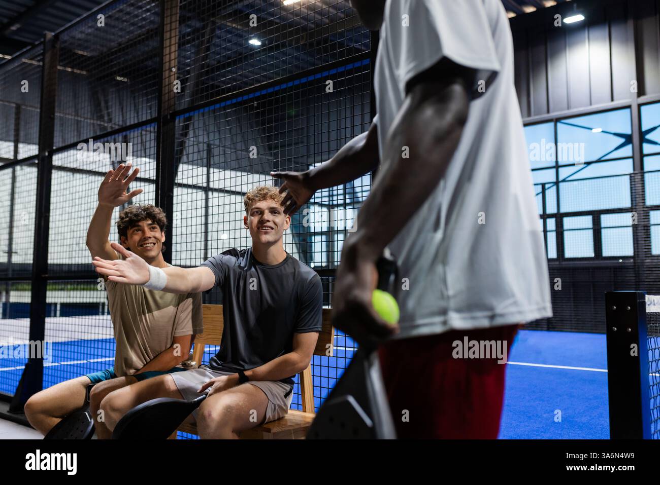 Friends enjoying padel tennis match, high-fiving and smiling on court ...