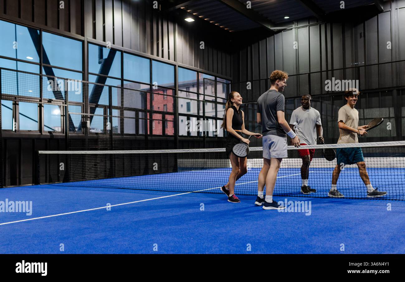 Group of friends playing padel tennis indoors, enjoying friendly match ...