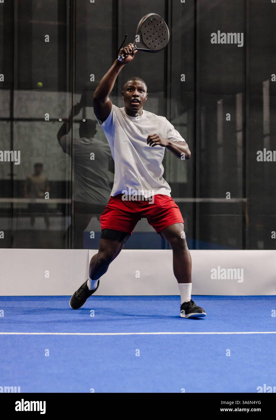 African American man playing padel tennis, focusing on hitting ball ...