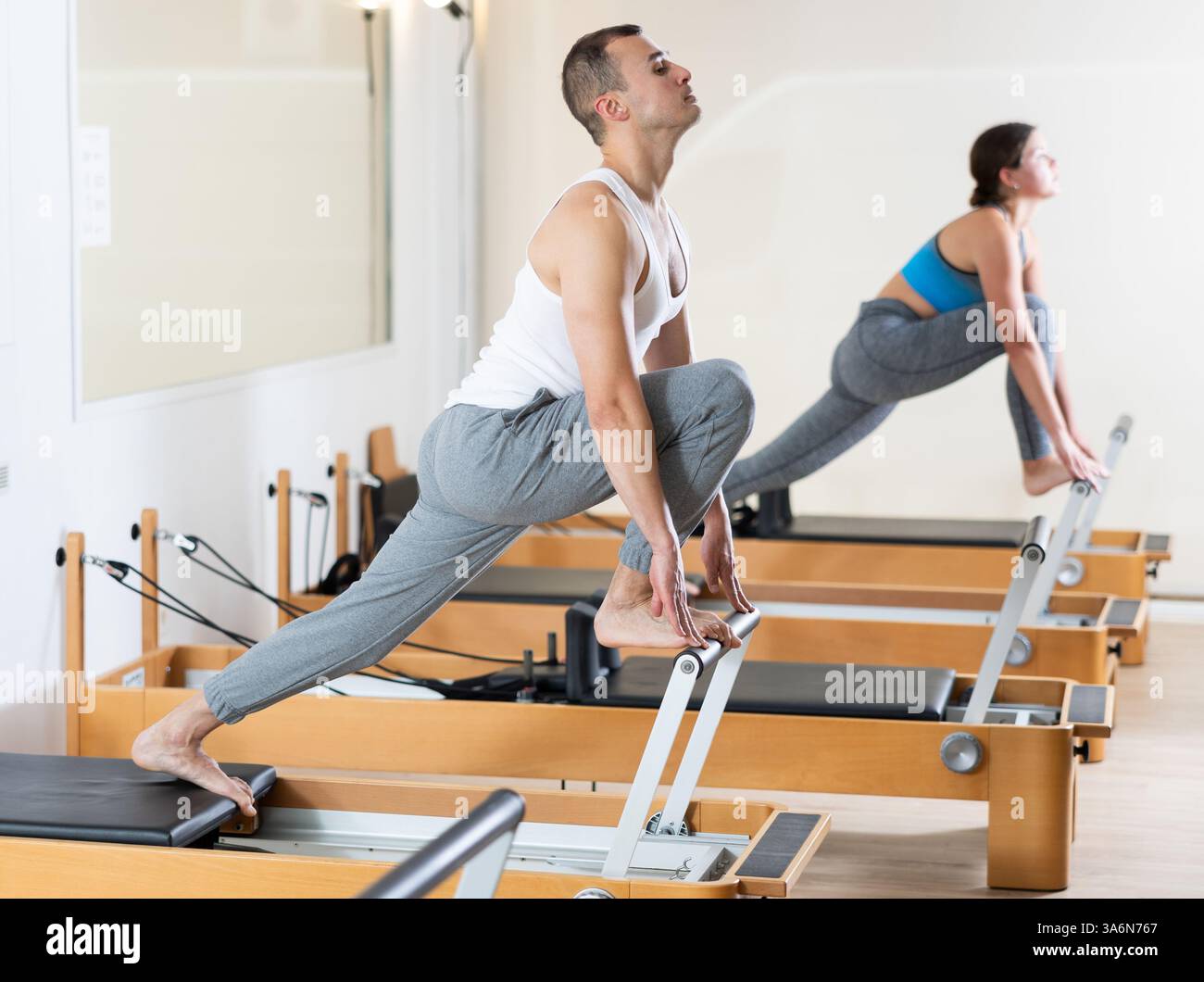 Sporty man in sports wear engages in Pilates on reformer machine Stock ...
