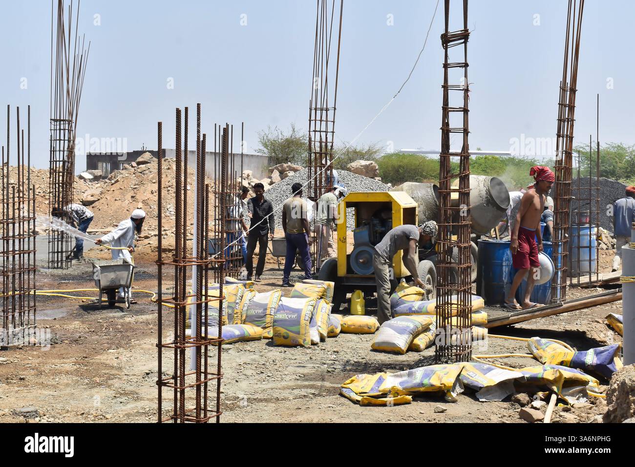 Construction workers at a building site with steel rods and cement bags ...