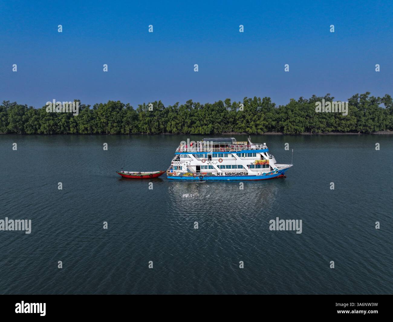 A tourist vessel anchored on a river beside the Sundarbans, the world's largest mangrove forest ...
