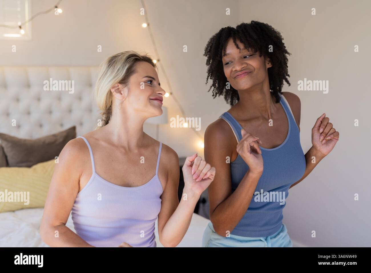 Two female friends dancing joyfully at home, enjoying fun moment ...