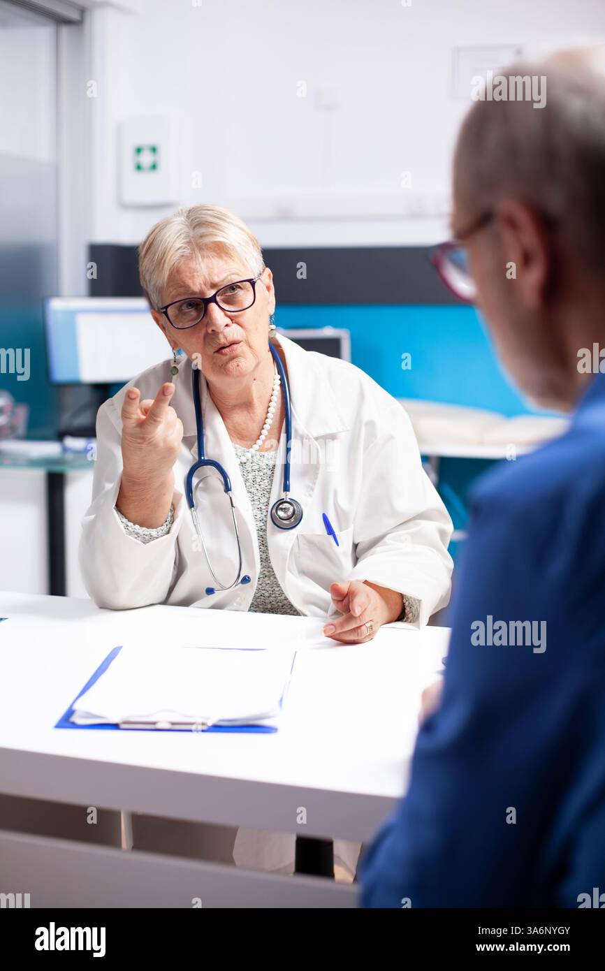Elderly doctor carefully explains healthcare treatment to pensioner ...