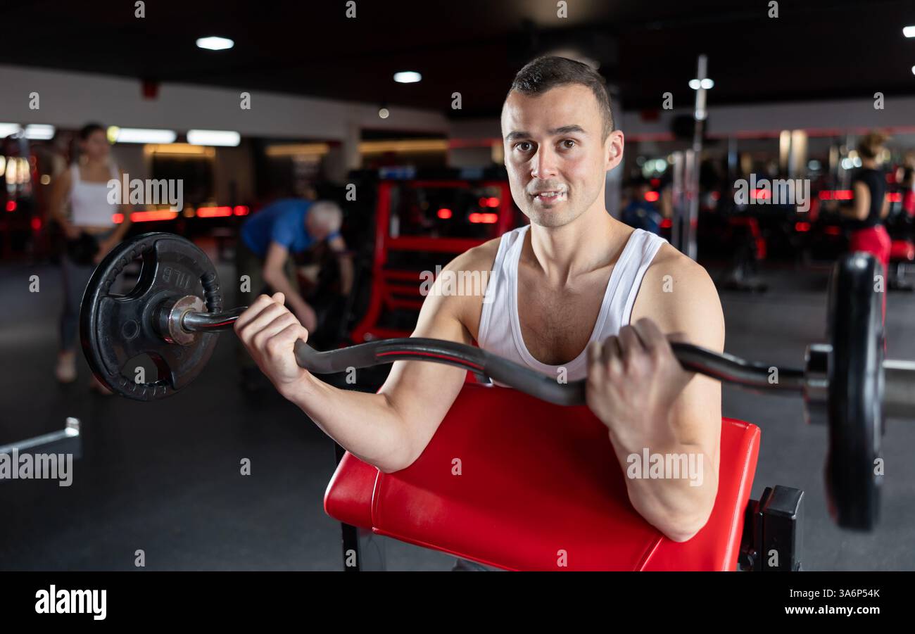 Sporty man performing set of exercises with barbell during intense ...