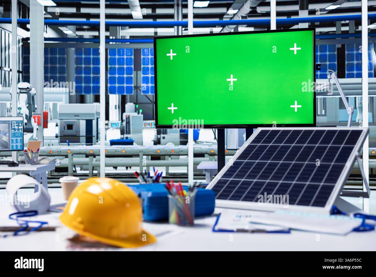 Green screen PC monitor in factory workspace with robotic machinery ...