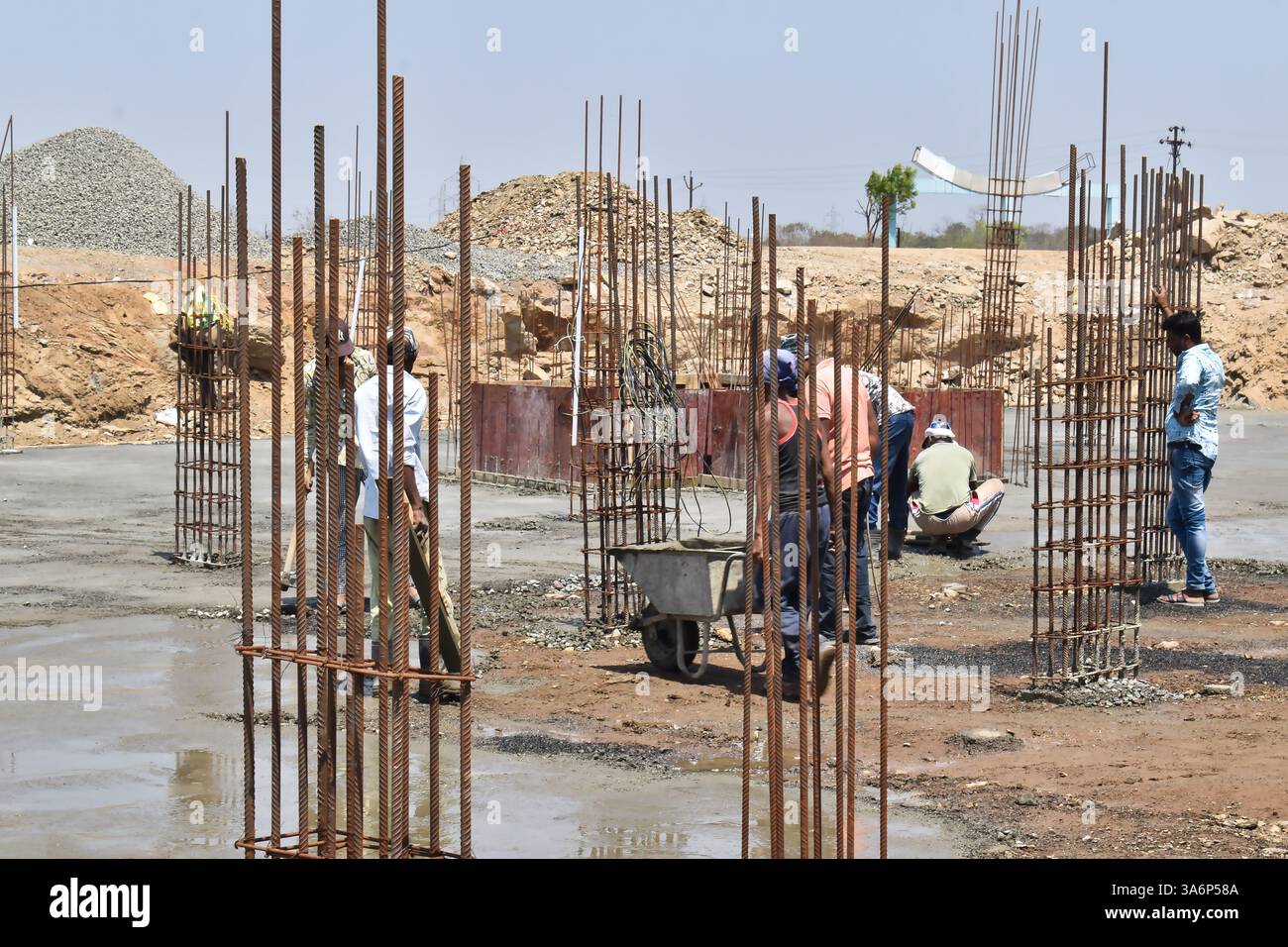 Construction site with workers and metal rebar structures on a concrete ...