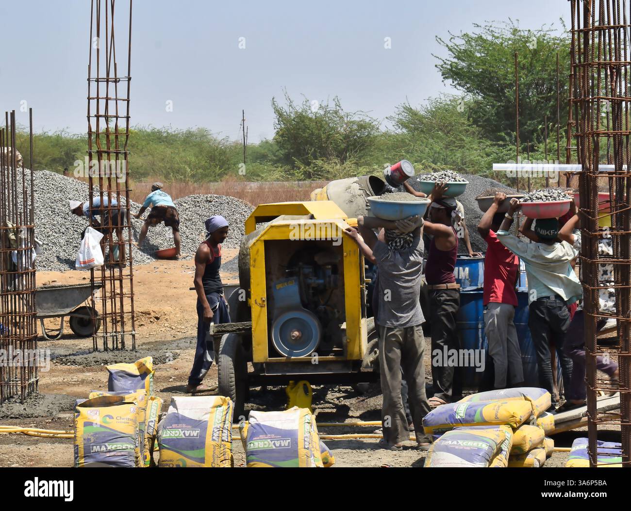 Construction workers carrying gravel and working at a building site ...