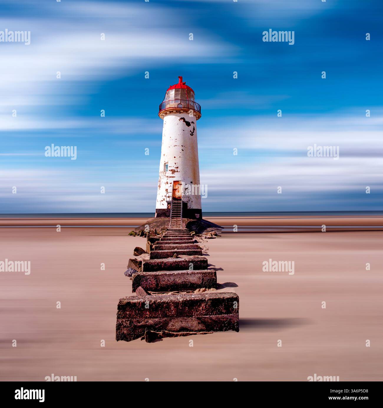 old white lighthouse with a red top and a concrete block pathway ...