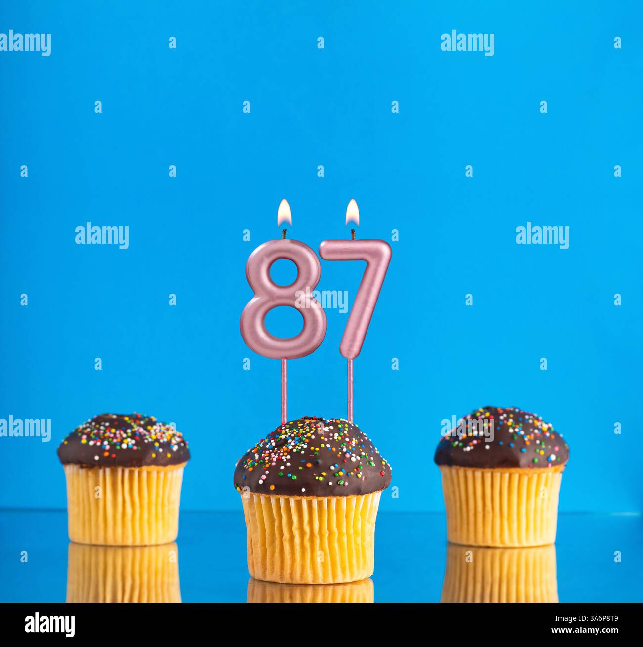 Three birthday cupcakes with number 87 candle - Blue background Stock ...