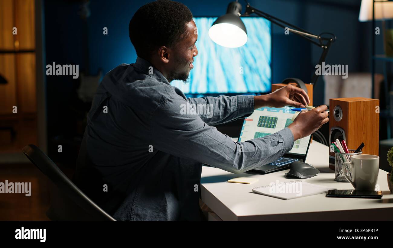 Black man organizing his schedule with a planner and putting a reminder ...