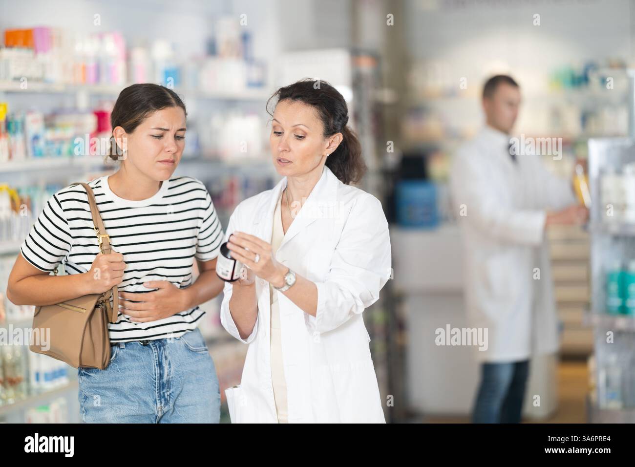 Female pharmacist advises medicine for stomach pain to woman Stock ...