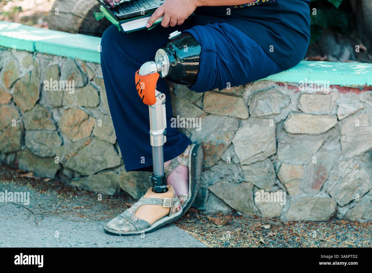 View of a Latina woman's prosthetic leg working on her computer in a ...